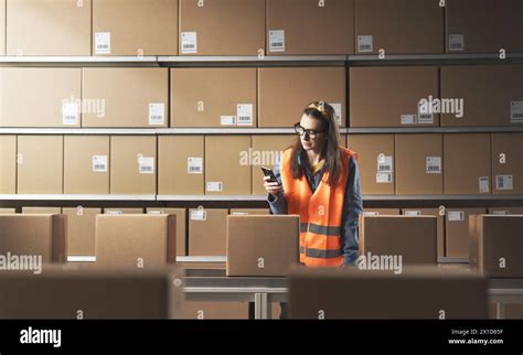 Bored Distracted Female Warehouse Worker Using Her Smartphone At Work