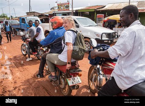 Women Passenger On Motorcycle Navigates Muddy Entebbe Streets In Uganda With Fellow Ridersshe