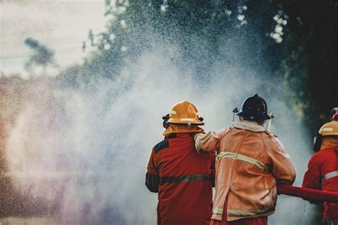 소방관은 소화기를 사용하여 호스에서 물을 분사하여 연료에 불꽃으로 소방을 하고 안전을 위해 화재를 진압합니다 공장에서 소방관을 교육합니다 소방관에 대한 스톡 사진 및 기타