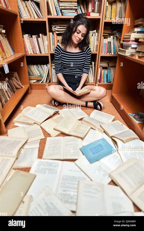 Attractive Young Woman In Striped Top And Black Mini Skirt In A Library