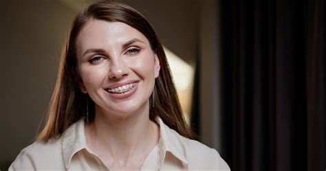 치과 교정기를 가진 젊은 여성이 손으로 심장 모양을 보여주고 있습니다 구강 위생 치과 치료 및 긍정적 인 감정의 개념 교정