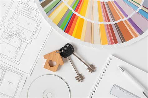 색상 가이드에서 인테리어 디자인의 색상을 선택하는 손 아파트 스케치 페인트 팔레트 집 모델 및 배경에 열쇠 고리 컬러 견본을 사용하는 건축가 블루프린트가 있는 하우스 플랜