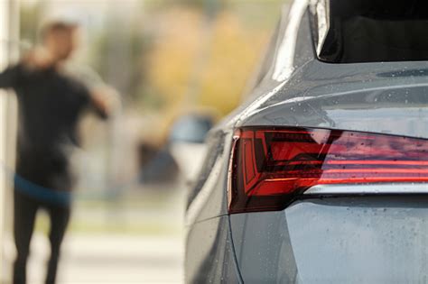 흐릿한 배경에서 남자와 함께 셀프 서비스 세차장에서 젖은 자동차 백라이트의 클로즈업 고압 청소에 대한 스톡 사진 및 기타 이미지 고압 청소 교통 관련 직업 교통수단