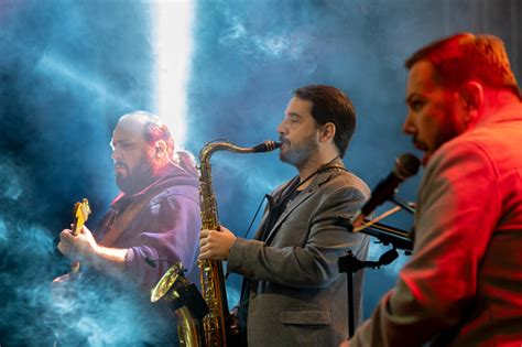 음악 밴드가 연주합니다 색소폰 연주자는 기타리스트와 피아니스트와 함께 그림의 중심 무대를 차지합니다 Performance Group에 대한 스톡 사진 및 기타 이미지