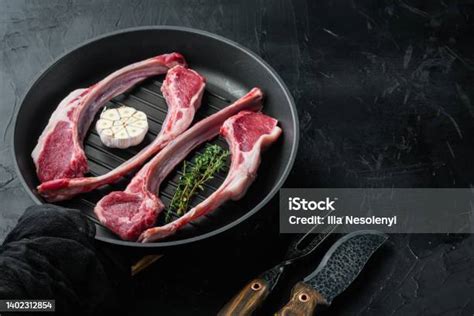 양고기 고기의 유기농 조각 양고기 랙 뼈와 함께 날것 재료 당근 오렌지 허브 튀김 주철 팬에 검은 돌 배경에 카피 스페이스와 텍스트를위한 공간 0명에 대한 스톡 사진 및