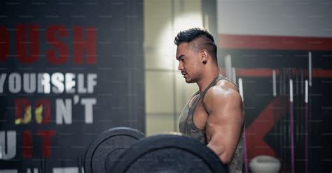 강한 젊은 운동 선수는 피트니스 체육관에서 바벨 무게를 들어 올리는 남자에 적합합니다 몸에서 근육질의 힘을 보여주는 운동복을 입은 남자 보디 빌딩 운동 및 스포츠 운동