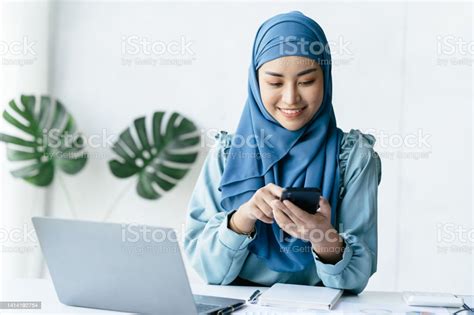 노트북 컴퓨터와 스마트 폰에서 일하는 무슬림 비즈니스 여성 Brand Name Smart Phone에 대한 스톡 사진 및 기타 이미지 Brand Name Smart