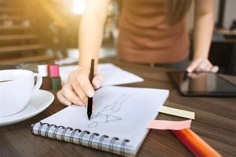 Premium Photo Midsection Of Fashion Designer Sketching On Spiral Notebook At Desk