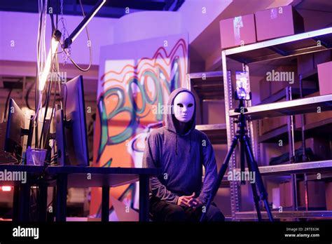 Anonymous Scammer Recording Video On Smartphone With Ransom Message In Abandoned Warehouse