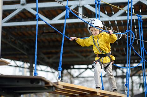 어린 소년은 어린이 아모웅 로프 계단 다리를 위한 어드벤처 파크에서 즐거운 시간을 보내고 있습니다 공공 공원에서 야외 등반 모험