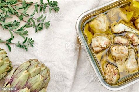 올리브 오일과 허브로 절인 아티 초크 하트 테이블 위의 유리 그릇에 마늘을 곁들인 절인 아티 초크 수제 건강한 식습관 건강관리와 의술에 대한 스톡 사진 및 기타 이미지