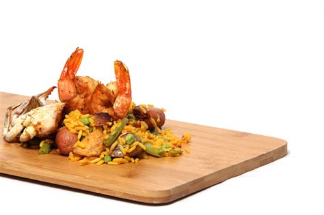 파에야 라이스는 소금 셰이커와 해산물 아마론 사프란 소시지 고기로 준비된 포크가 있는 나무 판에 제공됩니다 발렌시아 스페인 전통