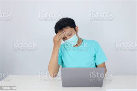 의료 용 마스크를 착용한 젊은 아시아 남자는 건강에 해롭고 피곤하며 테이블에 노트북을 작업하는 데 혼란스러워합니다 25 29세에 대한 스톡 사진 및 기타 이미지 Istock