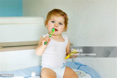 칫솔을 들고 첫 번째 치아를 닦는 어린 아기 소녀 우유 치아를 청소하는 법을 배우는 유아 예방 위생 및 의료 개념 욕실에서 행복한 아이 아기에 대한 스톡 사진 및 기타