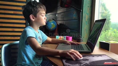 Boy Working At The Computer Stares At The Laptop Screen Doing