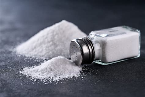 Spilled Salt And Salt Shaker On On A Black Stone Table Selective Focus