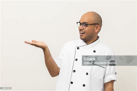 미소 짓는 젊은 잘 생긴 아시아 남자 요리사는 안경을 착용하고 서있는 채로 손바닥을 들고 고립 된 메뉴를 들고 게시합니다 요리 남자 직업 요리사 부엌 레스토랑과 호텔에있는