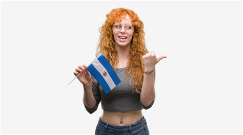 Young Redhead Woman Holding Flag Of Argentina Pointing And Showing With