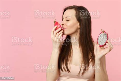 웃는 젊은 여자 들고 스튜디오에서 분홍색 파스텔 벽 배경에 고립 된 용 과일 신선한 익은 피타 하 야의 Halfs 스니핑 사람들은 생생한 라이프 스타일 휴식 휴가 개념입니다