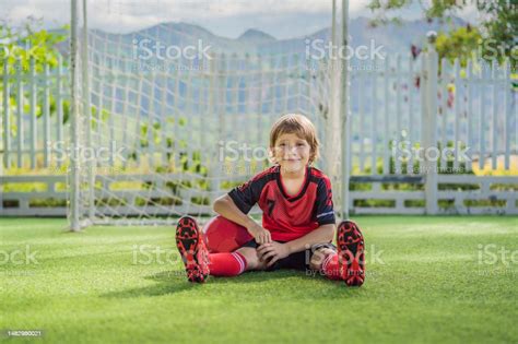 빨간 축구 유니폼을 입은 귀여운 소년이 야외에서 축구 축구를 하고 있다 아이들이나 아빠와 함께 스포츠를 하는 활동적인 아이 여름에 즐거운 미소를 짓는 행복한 소년 6 7