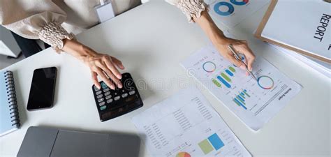 Businessman Analyzing Financial Data With Calculator And Charts In Modern Office Setting Stock