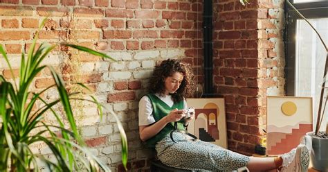 어두운 긴 물결 모양의 머리를 가진 젊은 여자는 넓은 로프트 아파트의 벽돌 벽에 기대어 앉아 복고풍 사진 카메라를 손에 들고 있다 사진 Unsplash의 벽돌 벽 이미지