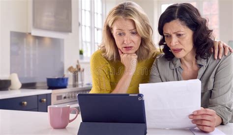Same Sex Mature Female Couple Using Digital Tablet At Home To Check