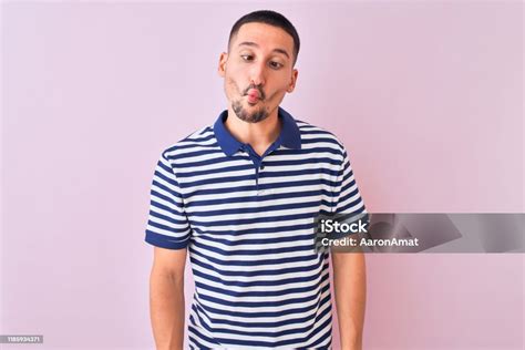 젊은 잘생긴 남자는 입술 미친 코믹 제스처와 물고기 얼굴을 만드는 분홍색 고립 된 배경 위에 해상 줄무늬 티셔츠를 입고 재미있는 표현 T 셔츠에 대한 스톡 사진 및 기타