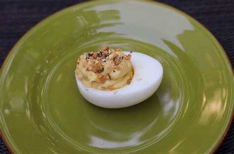 Deviled Eggs On A Green Plate Topped With Nuts