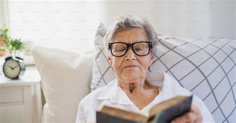 안경을 쓴 아픈 노인 여성이 집이나 병원에서 침대에 누워 성경을 읽고 있습니다 사진 Unsplash의 퇴직 이미지