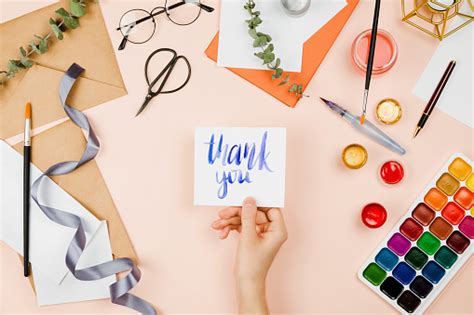 아트와 세련 된 Flatlay 공급 봉투 브러쉬 수채화 안경 펜 및 여자의 손을 잡고 Handlettered 비문 감사 합니다와 수 제 카드 파스텔 배경 가위에 대한 스톡