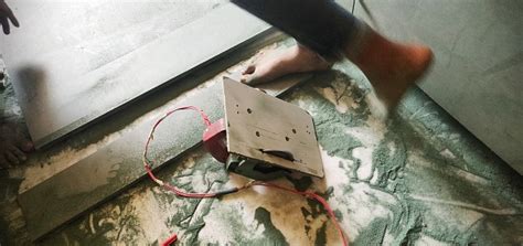 작업 진행 중 원형 전기 톱 기계가있는 건설 현장에서 목수의 작업 초록색의 나무 판자 또는 널빤지와 함께 지저분한 방식으로 흩어져있는 톱밥과 전선과 기계 근처에서 맨발로