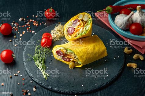 샤와르나 부리토는 양상추를 곁들인 훈제 소시지와 검은 색 배경에 노란 피타에 달걀을 더합니다 길거리 음식 0명에 대한 스톡 사진