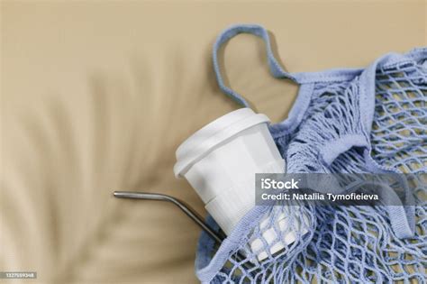 베이지 색 배경에 파란색 재사용 가능한 면 메쉬 백과 커피 머그잔 친환경 쇼핑백 닫습니다 제로 폐기물 식료품 개념 플라스틱이 없는 지속 가능한 라이프스타일 0에 대한 스톡