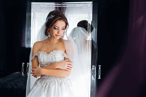 하얀 드레스를 입은 긴 머리를 가진 아름다운 젊은 여자가 거울에 비친다 결혼식 전 신부의 아침 아름다운 메이크업 신부에 대한