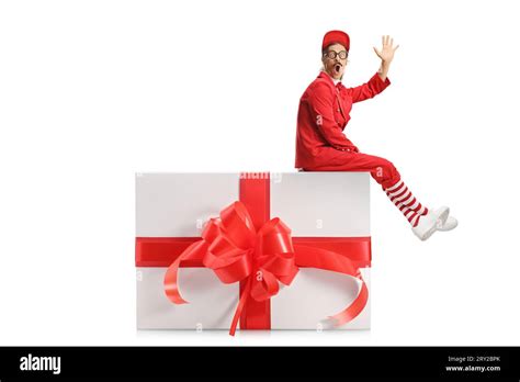 Entertainer In A Red Suit Sitting On A Big Present Box And Waving