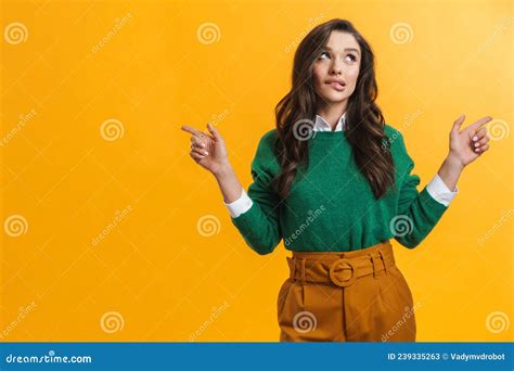 Young Woman Biting Her Lip And Pointing Fingers At Opposite Sides Stock