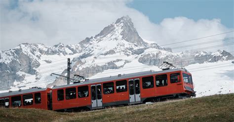 눈 덮인 산을 지나가는 빨간 기차 사진 Unsplash의 체르마트 이미지