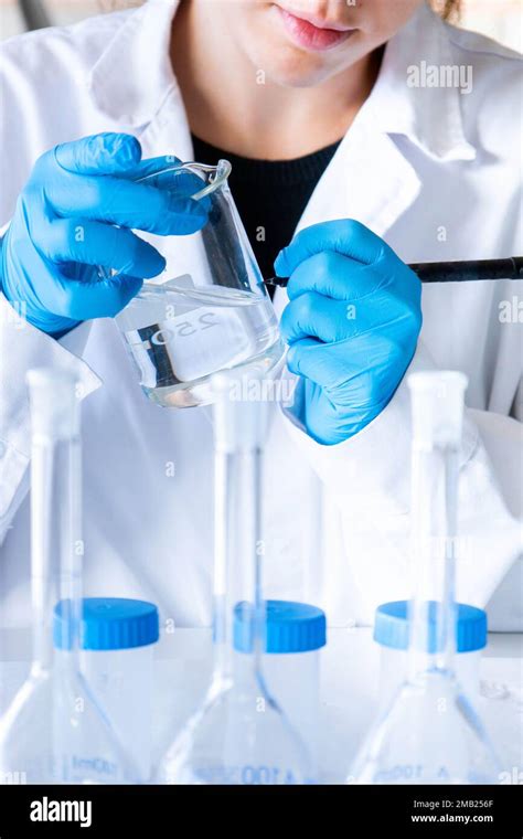 Close Up Left Handed Woman Scientist Labeling Beaker Samples With Blue