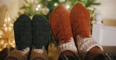 축제 저녁 방의 조명에서 크리스마스 트리를 배경으로 아늑한 모직 양말을 신은 커플 겨울 방학을 함께 축하하고 집에서 아늑한 가족의 순간 세련 된 따뜻한 양말 사진