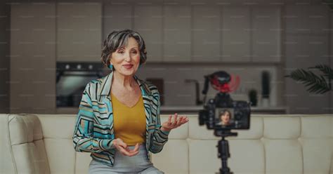 거실에서 카메라를 사용하여 비디오 콘텐츠를 만드는 세련된 노인 여성 소셜 미디어 개념입니다 사진 Unsplash의 사업 이미지