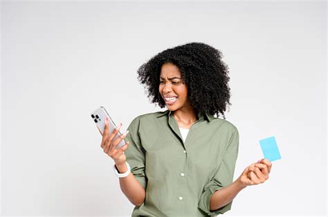 자신감 넘치는 아프리카계 미국인 사업가가 신용카드를 들고 당황한 듯 휴대전화를 보며 눈살을 찌푸린다 20 24세에 대한 스톡