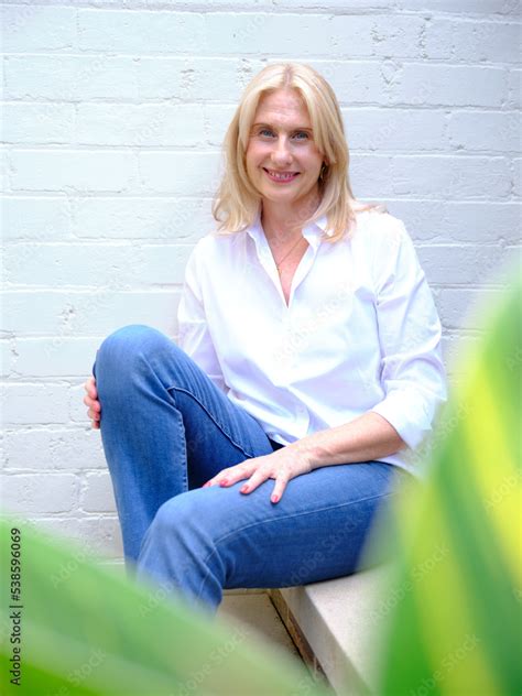 Smiling Blonde Middle Aged Woman Wearing Shite Shirt And Blue Jeans