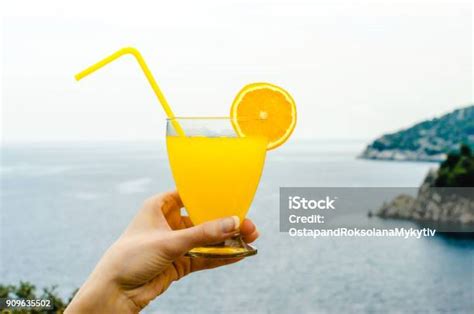 다이어트입니다 건강 한 먹는입니다 여자 손 칵테일 유리 배경 흐리게 바다 야생 자연 야외 비치에서 레모네이드 음료를 들고 신선한 해독 야채 오렌지 주스입니다 건강 한 생활