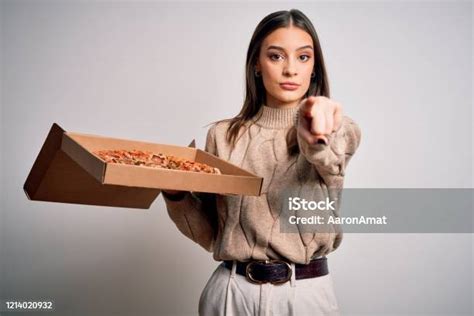 젊은 아름 다운 갈색 머리 여자 들고 상자 위에 흰색 배경 카메라와 당신에 게 손가락으로 가리키는 손 기호 앞에서 긍정적이 고 자신감 제스처 갈색 머리에 대한 스톡 사진 및