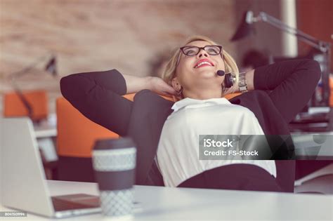 아름 다운 젊은 여 자가 사무실에 그녀의 장소에 앉아있는 동안 웃 고 머리 뒤에 손을 잡고 금발 머리에 대한 스톡 사진 및 기타