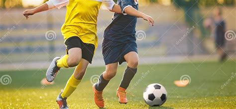 2 Футболиста в поединке на месте травы Мальчики работающих после черно белого футбольного мяча