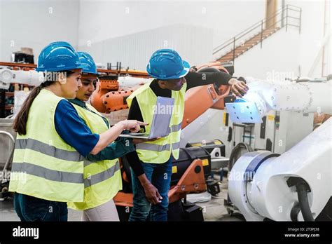 Multiracial Engineers Working With Robot Arm At Robotic Warehouse Facility People And