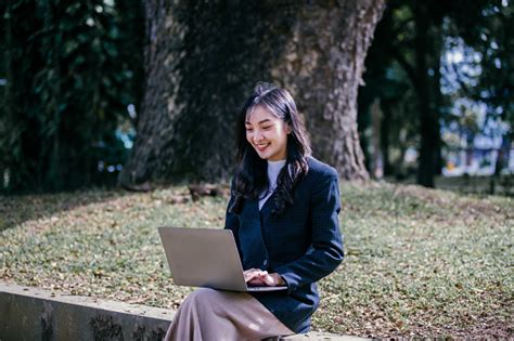공원의 낮은 벽에 앉아 노트북으로 작업하면서 신선한 공기를 마시고 평화로운 자연 환경을 즐기며 미소 짓는 젊은 사업가 30 34세에 대한 스톡 사진 및 기타 이미지 Istock