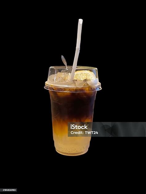검은 배경에 고립 된 레몬 소다를 곁들인 아이스 블랙 커피 커피는 플라스틱 유리를 가져갑니다 음료 메뉴 바닥에 레모네이드 층이
